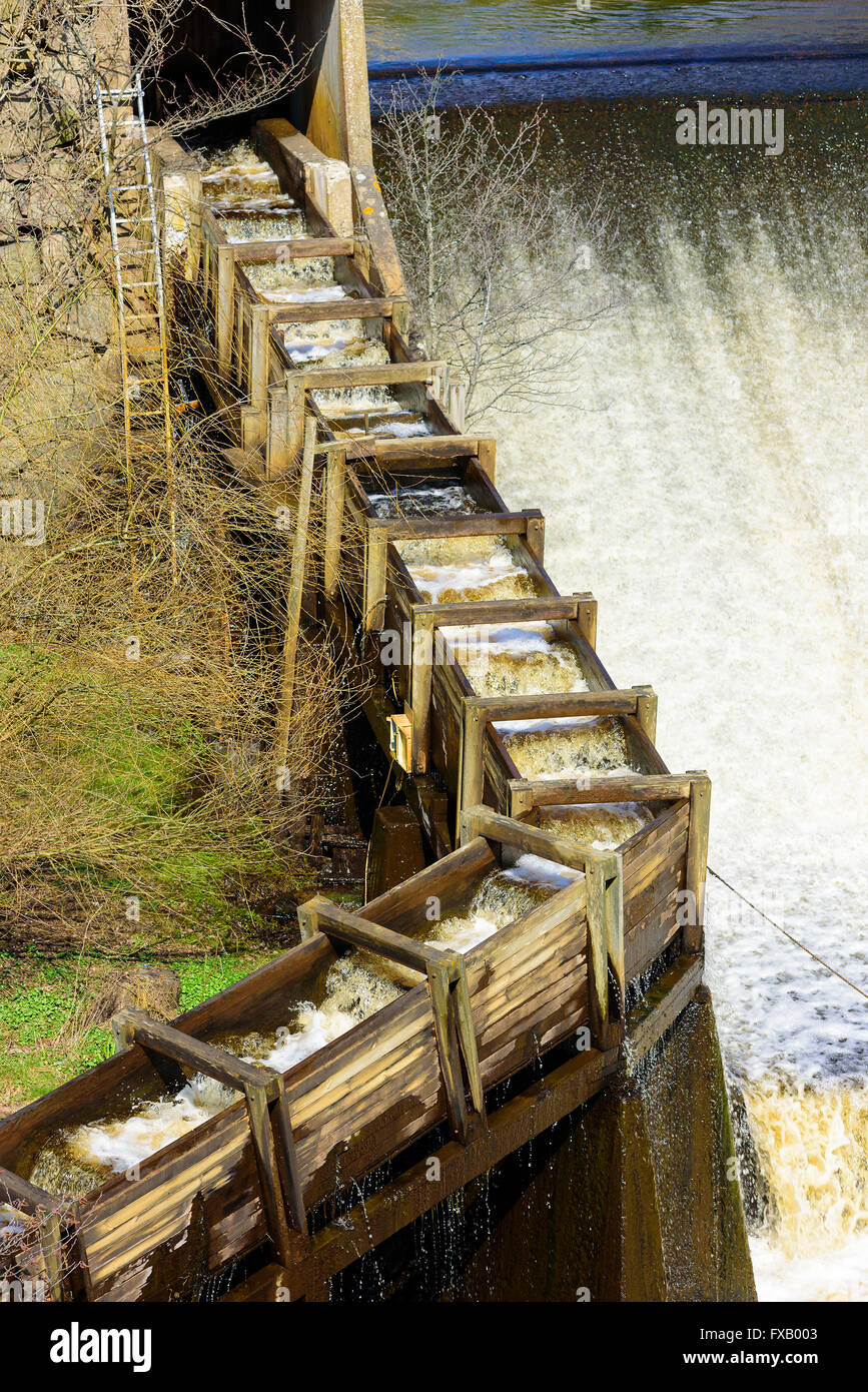 Wooden fish ladder with flowing water beside a reservoir overflow. This ...