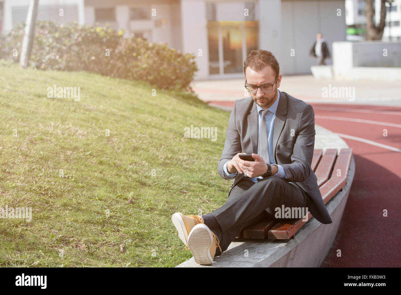 Businessman using his smart phone while resting on the bench Stock ...