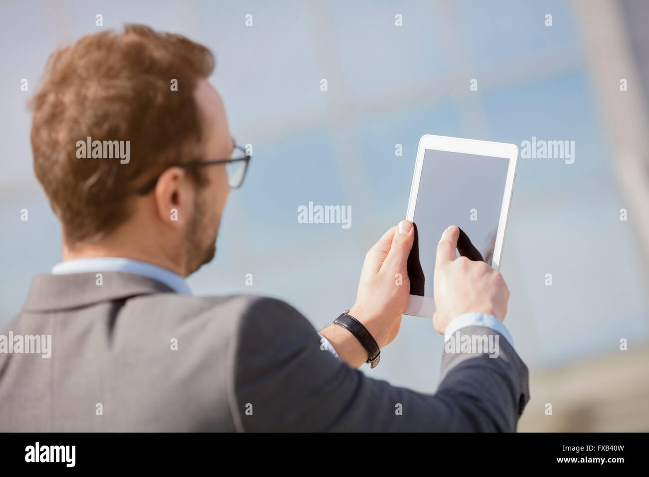 Manager using digital tablet device in front of the business building ...