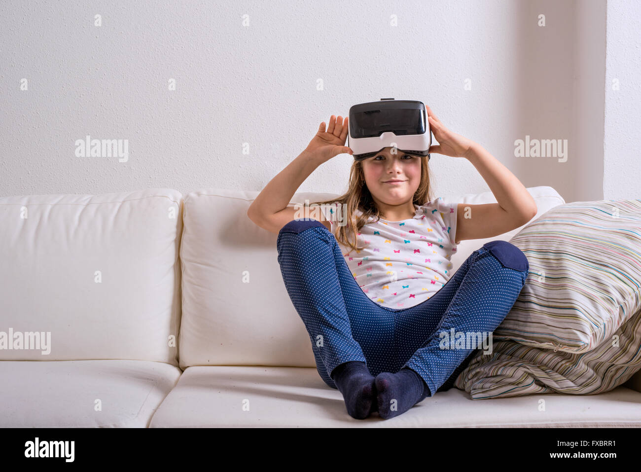 Girl wearing virtual reality goggles. Studio shot, white couch Stock ...