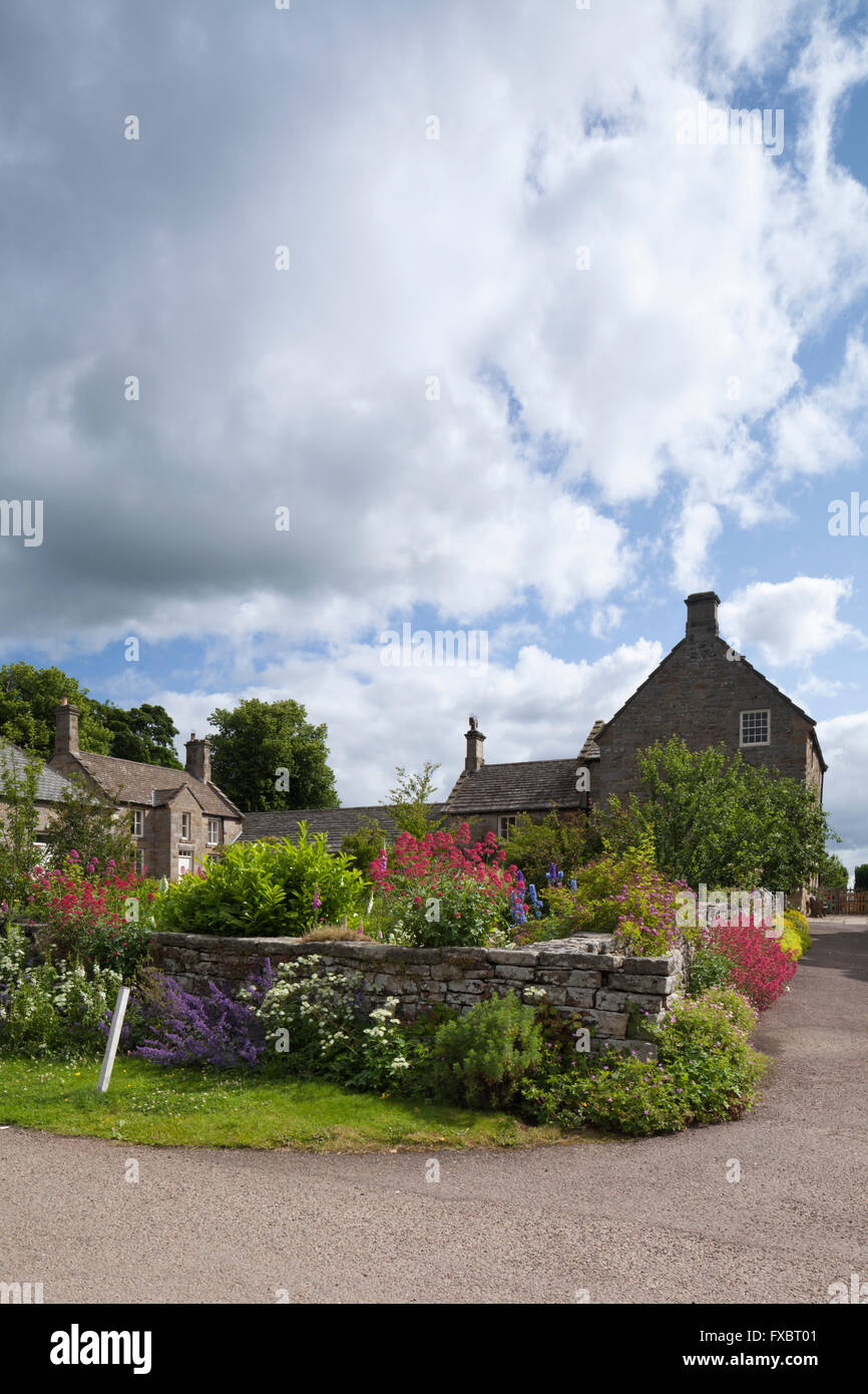 Stone cottages clustered around the colourful village garden square in ...
