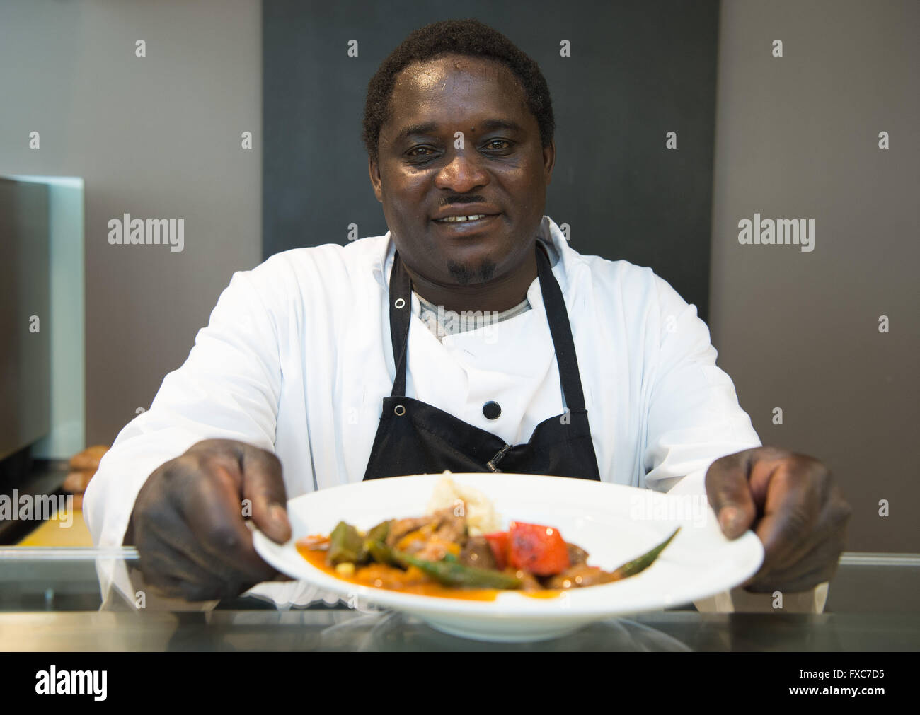 Sudanese chef Hassan Abakar Omar hands a plate of lamb ragout with okra ...