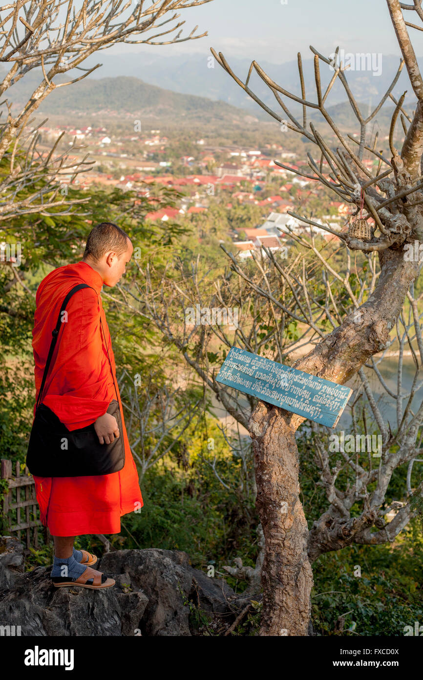 Buddhist monk standing on rock reading sign Phousi Mountain Laos Stock ...