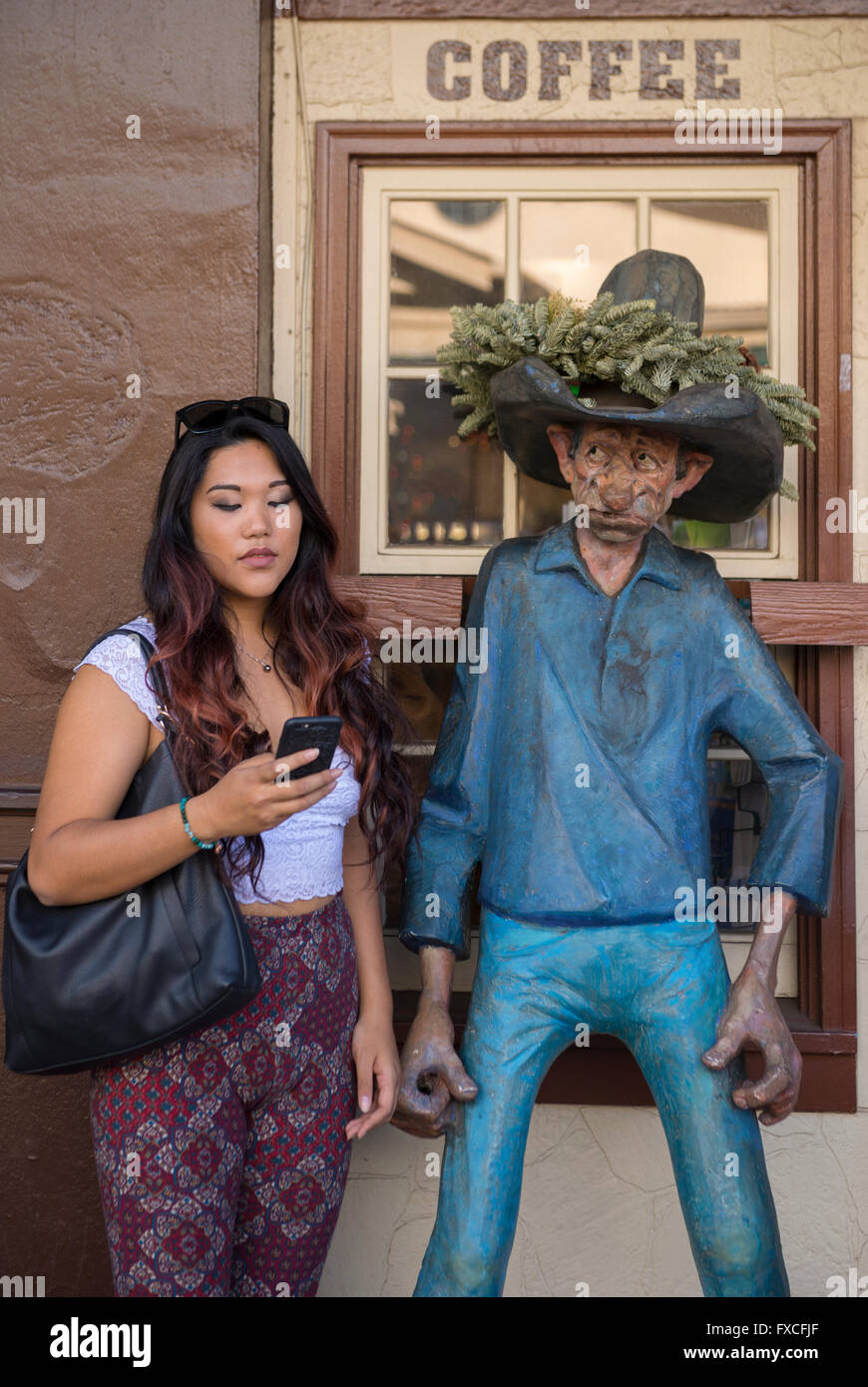 USA, Hawaii, Maui, island, Lahaina, woman texting next to wood ...