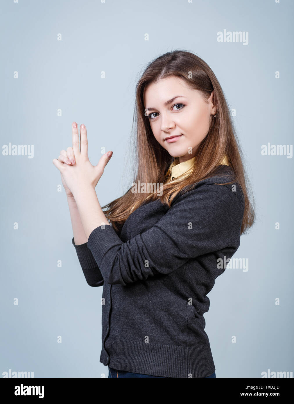 Young beautiful woman showing gun gesture Stock Photo - Alamy