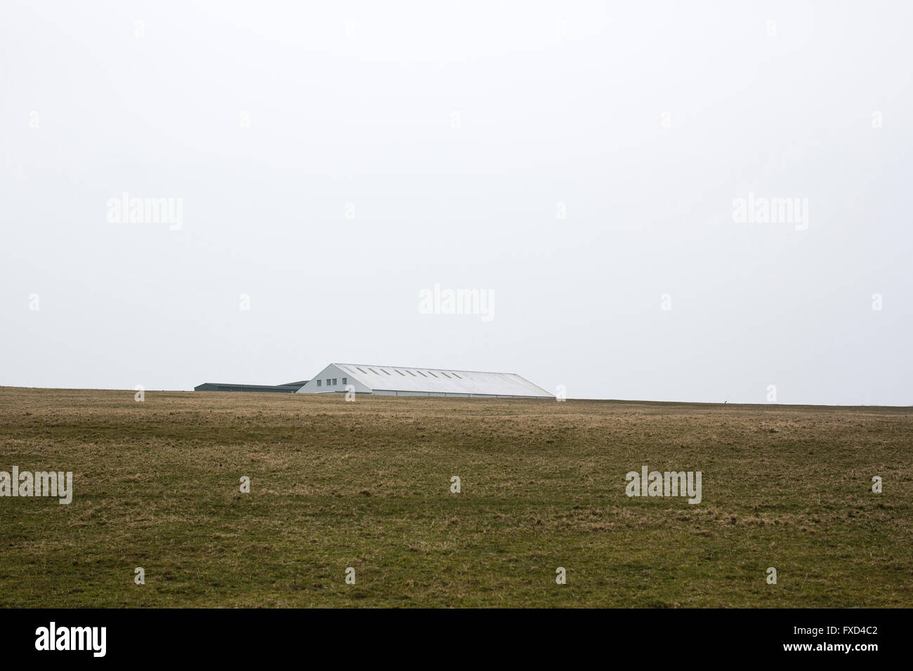Large barn, warehouse or shed half hidden over the horizon in a field ...
