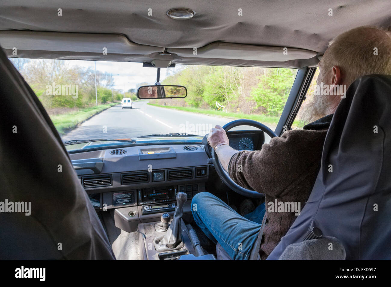 Man driving a car on a road, Nottinghamshire, England, UK. Viewed from ...