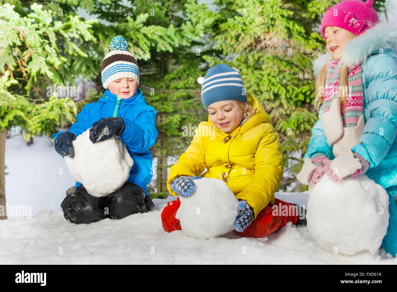 Kids roll snow balls in the park Stock Photo - Alamy