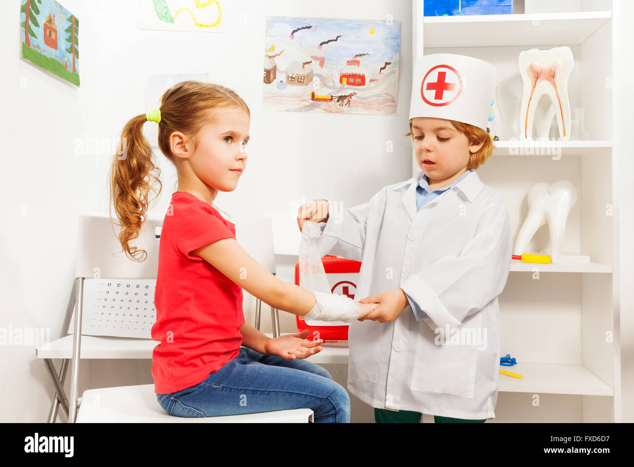 Little pediatrician doctor bandaging girl's arm Stock Photo - Alamy