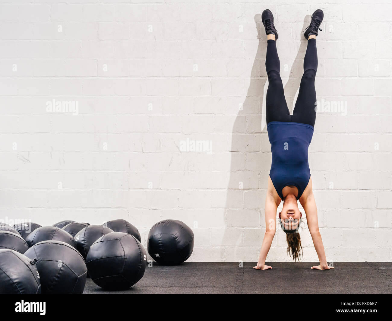 Photo of a young fit woman doing a handstand exercise at a crossfit gym ...
