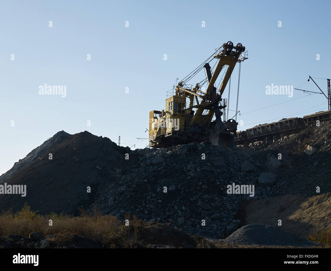 Quarry excavator on the ore dump with railroad platform wagon in the ...