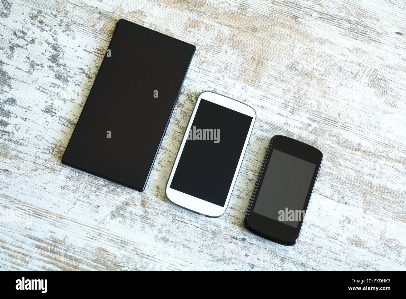Three smartphone in different sizes on a wooden table Stock Photo - Alamy