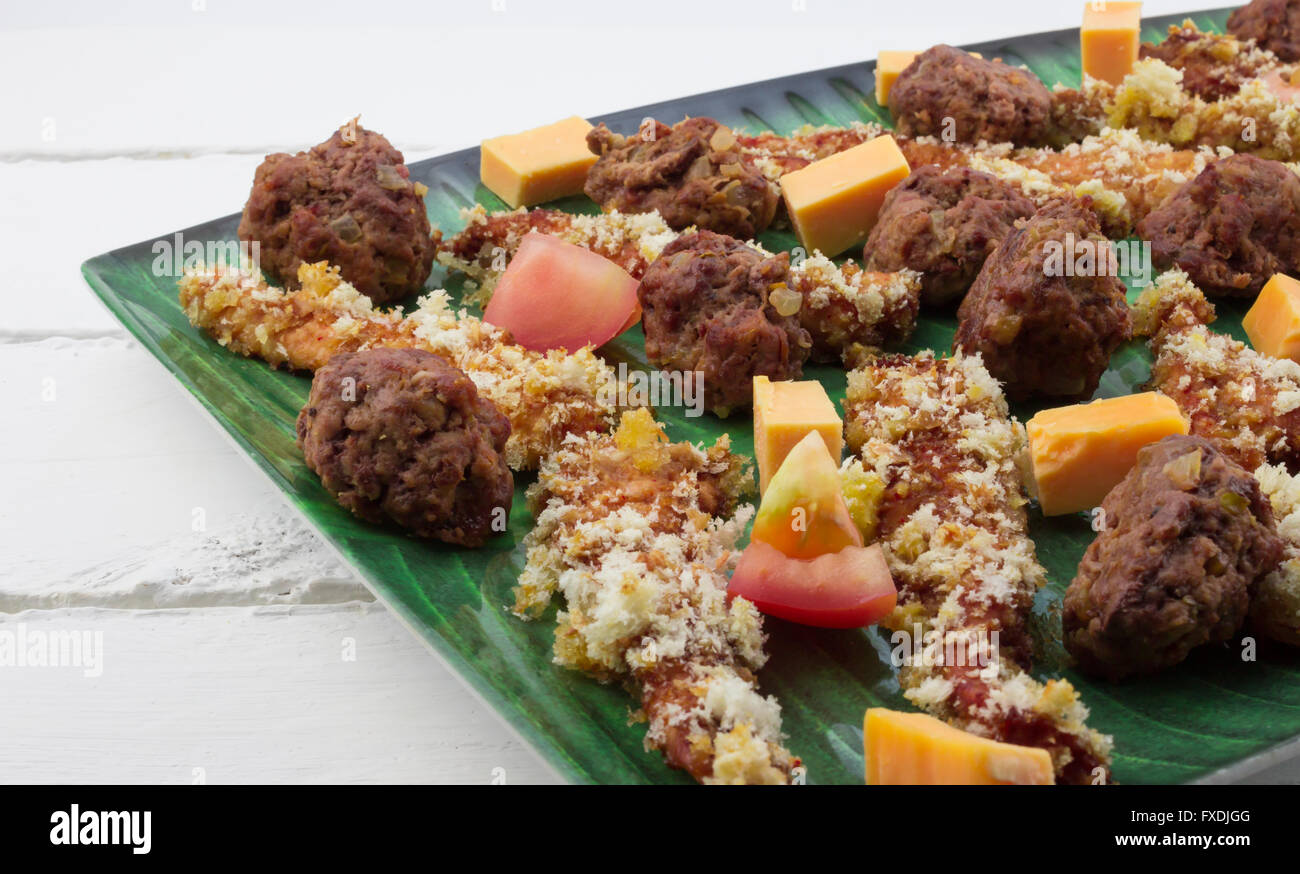 Close up of savoury canapes on a green platter on white wood table ...
