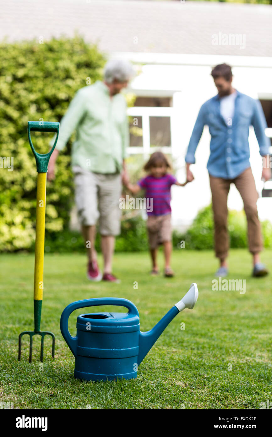 Rake and watering can with family walking in yard Stock Photo - Alamy