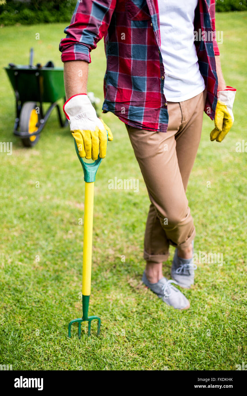 Man standing with rake in yard Stock Photo - Alamy