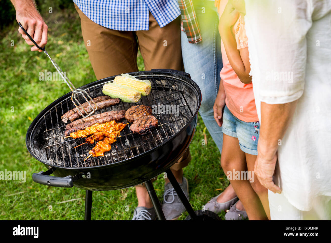 Man preparing food on barbecue grill by family Stock Photo - Alamy