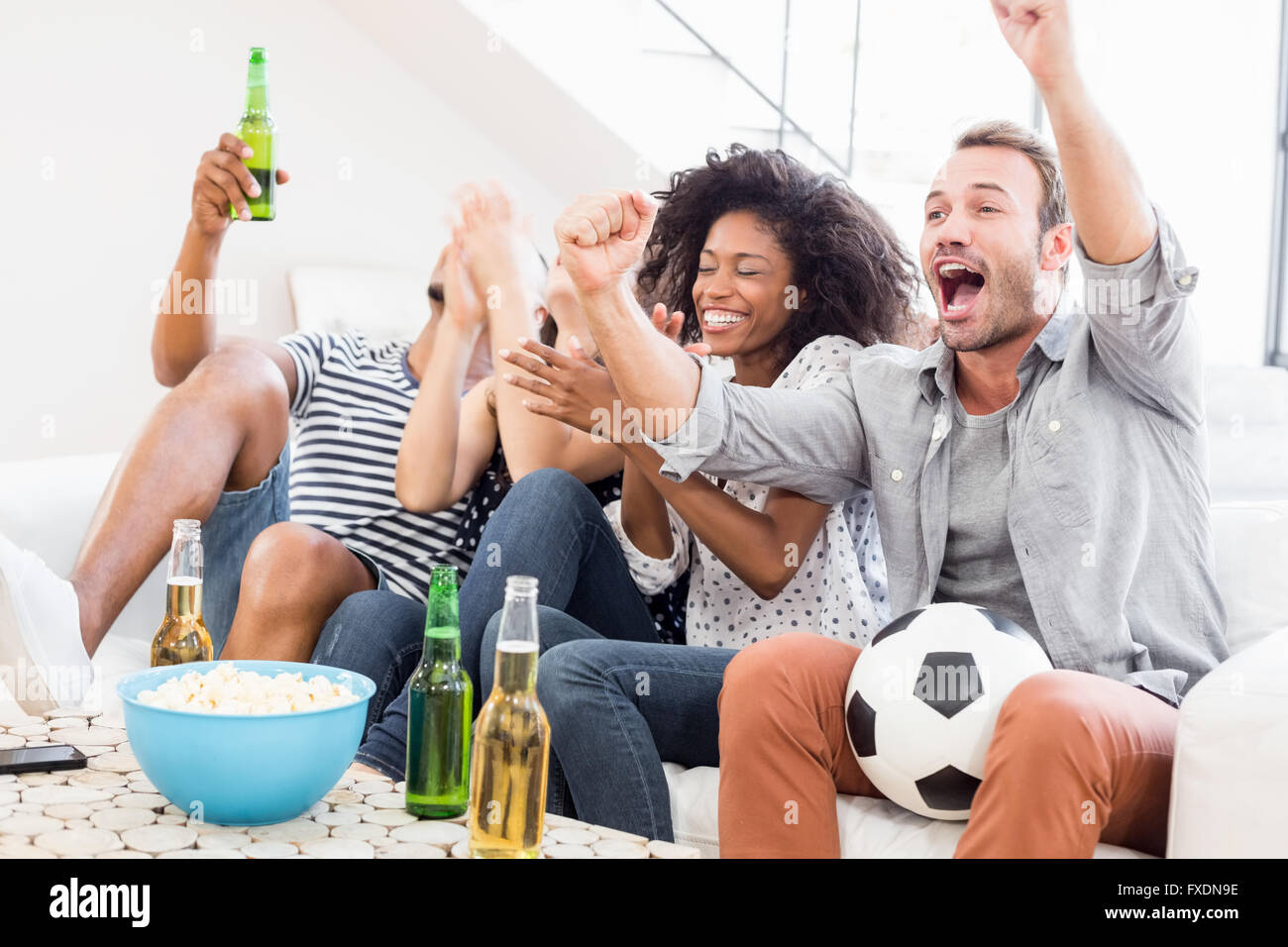 Excited friends cheering while watching television Stock Photo - Alamy