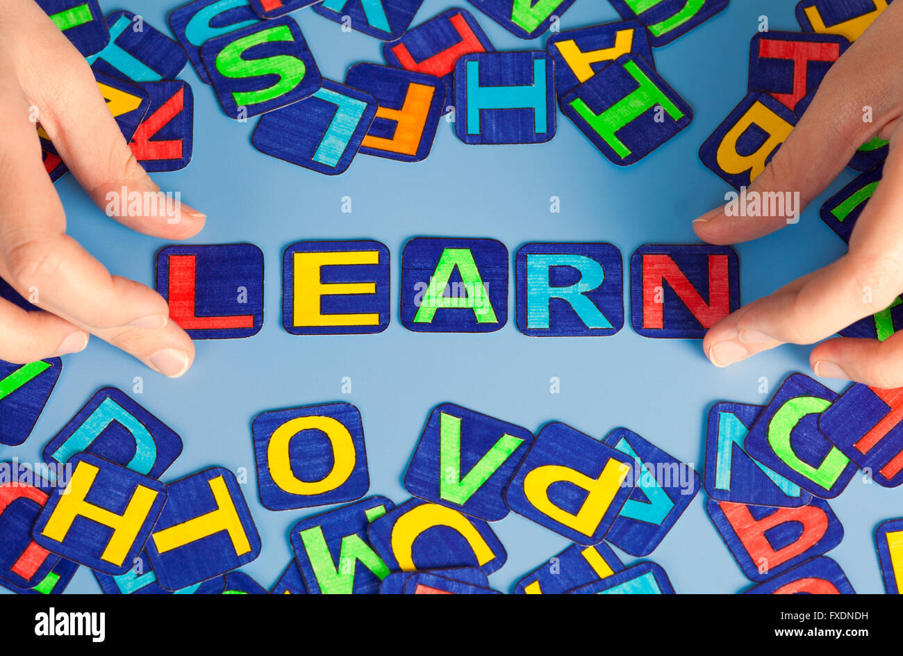 Word Learn spell out on blue table with woman hands and letters ...