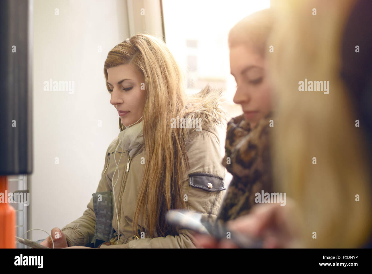 Single blond woman in gray winter coat sitting inside crowded commuter ...