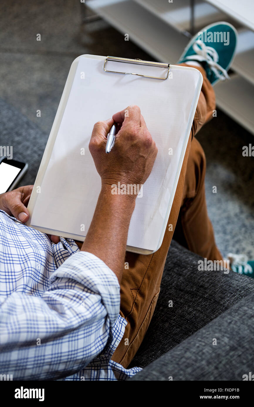 Man writing note on clipboard Stock Photo - Alamy