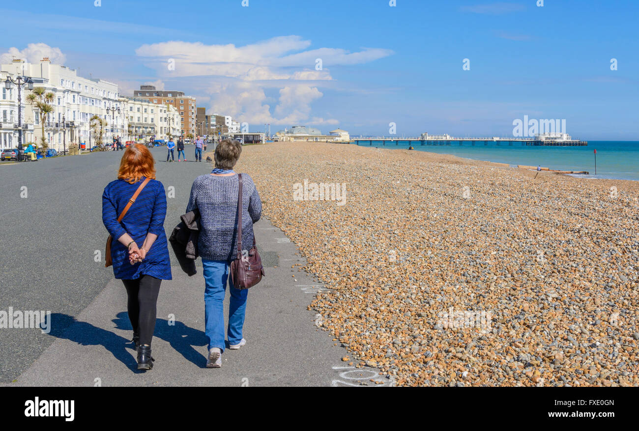 Couple of women walking along the promenade at the seaside on a sunny ...
