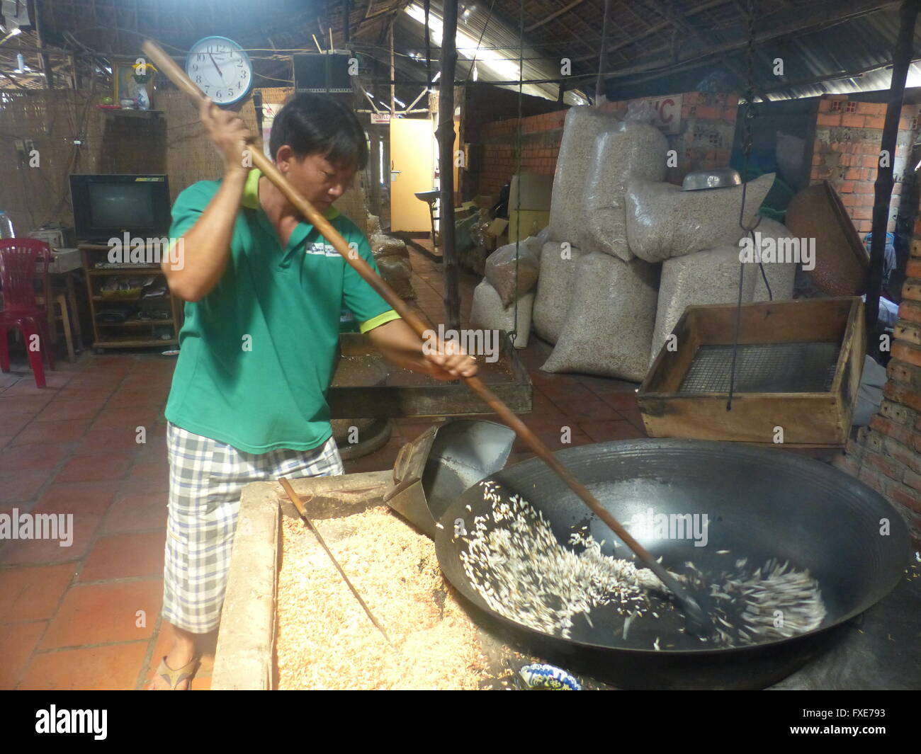 Vietnamese worker stirs rice beans in wog pot to make puffed rice Stock ...