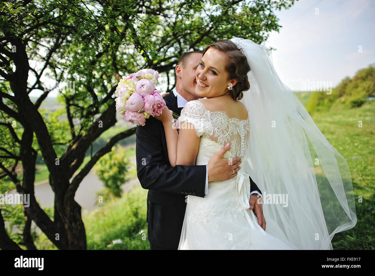 Groom kissing neck of bride background landscape with river Stock Photo ...