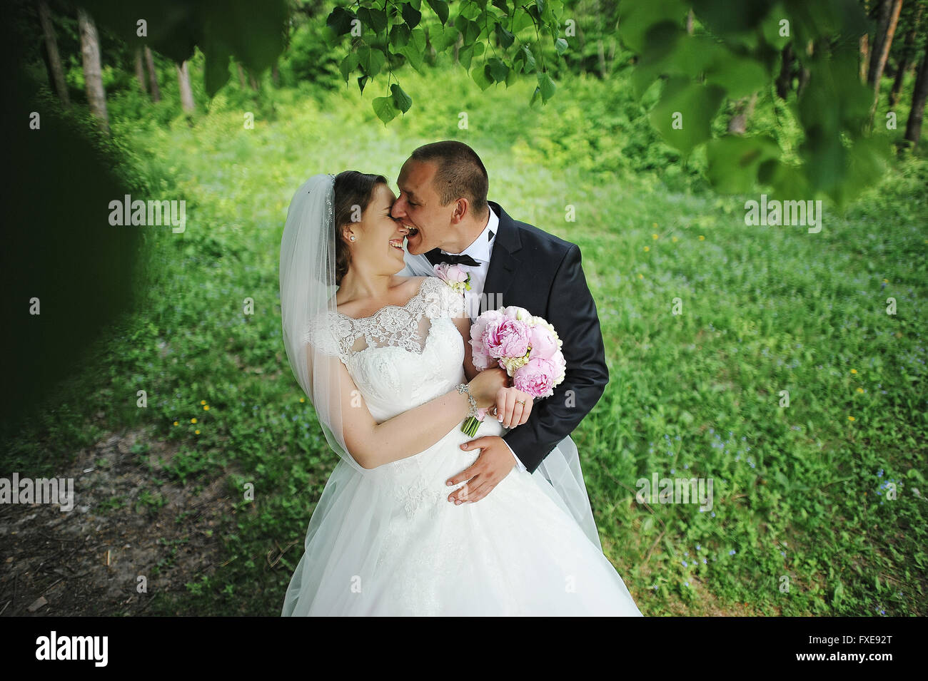 Funny wedding couple at forest, groom biting nose of bride Stock Photo ...