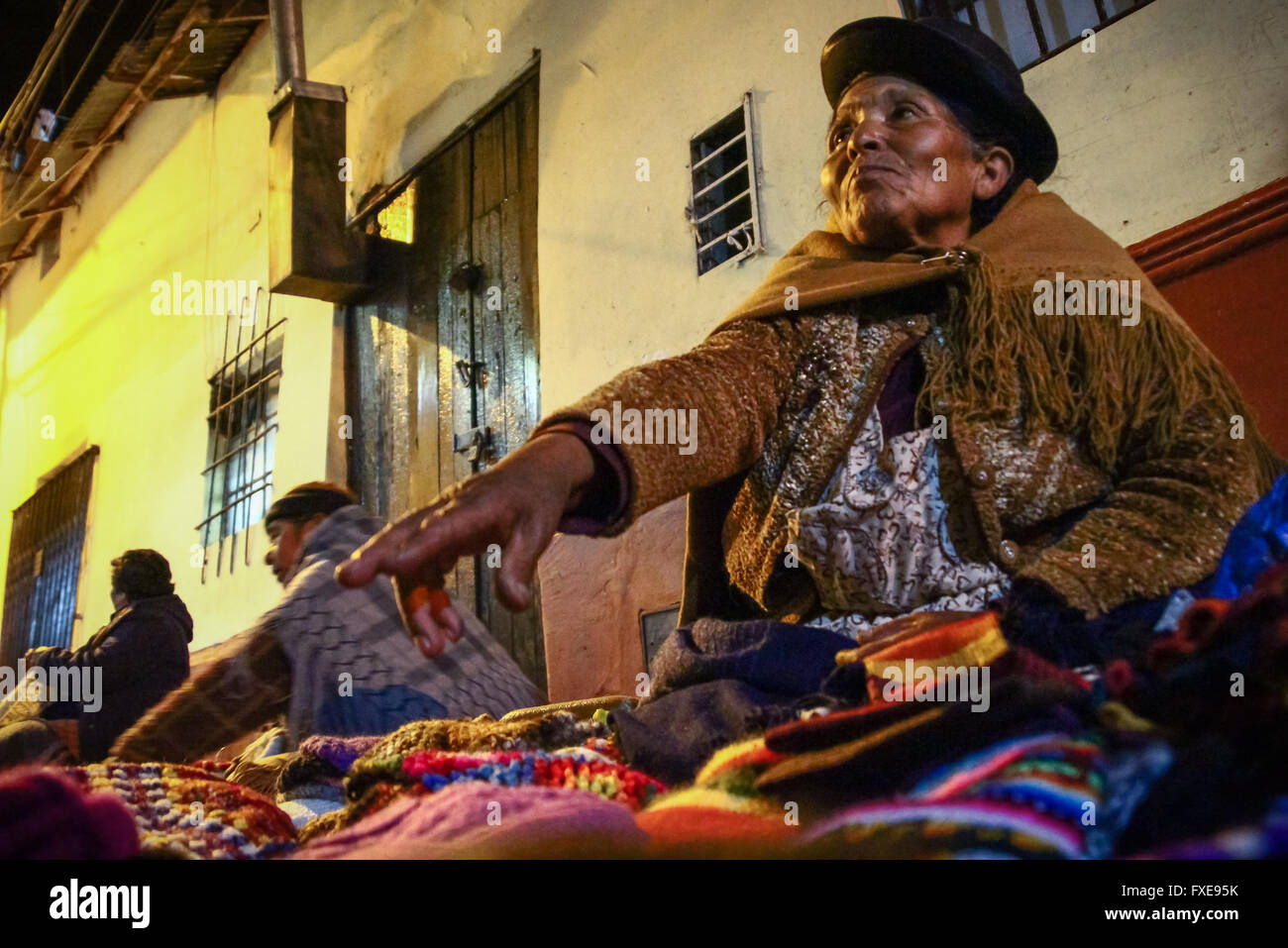 an old women selling a typical textile on the street in the evening ...