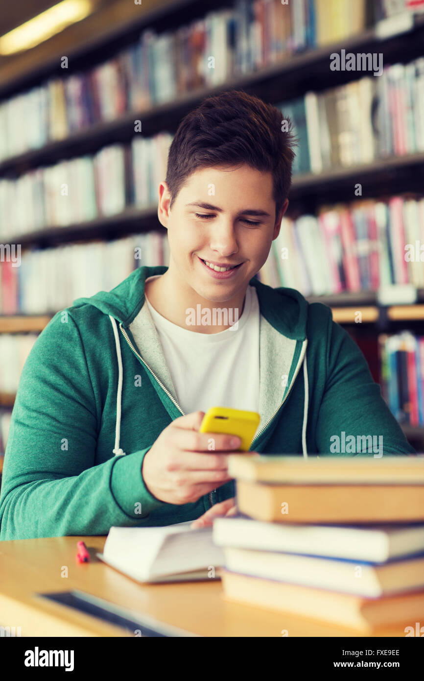 male student with smartphone texting in library Stock Photo - Alamy