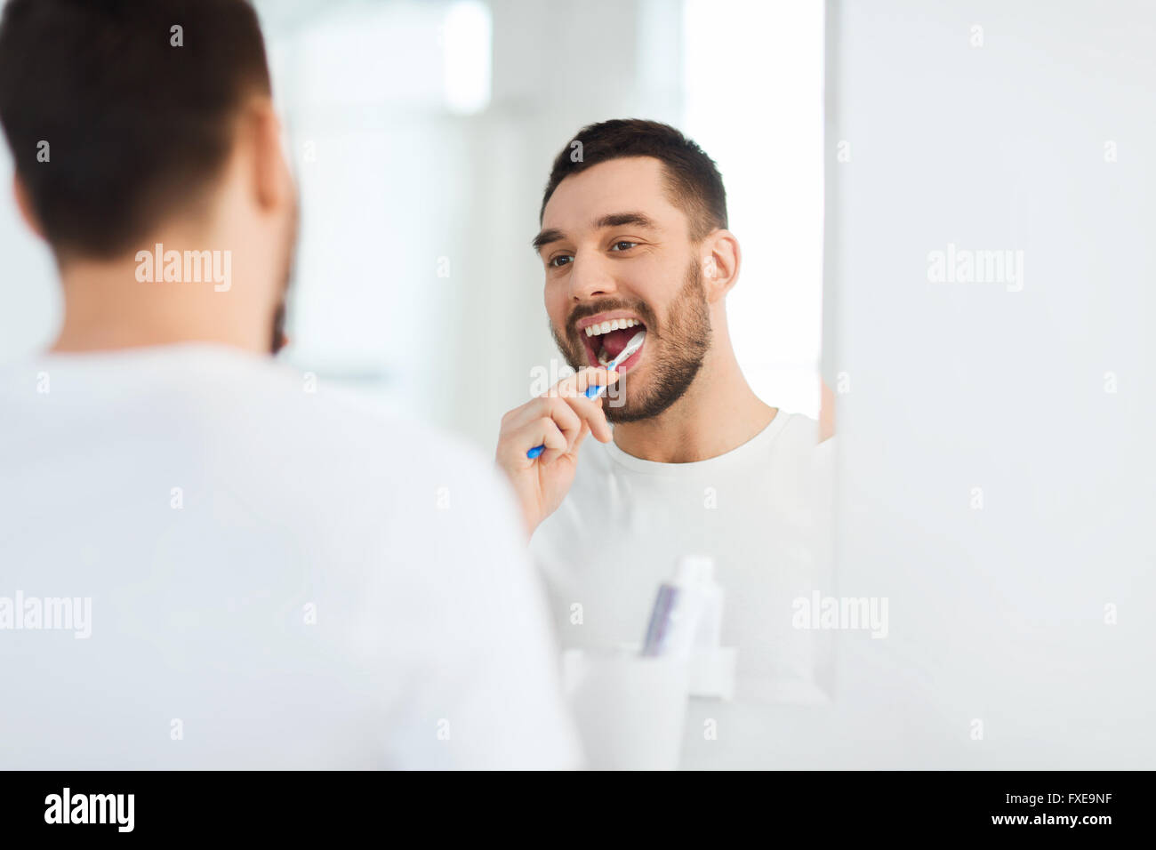 man with toothbrush cleaning teeth at bathroom Stock Photo - Alamy