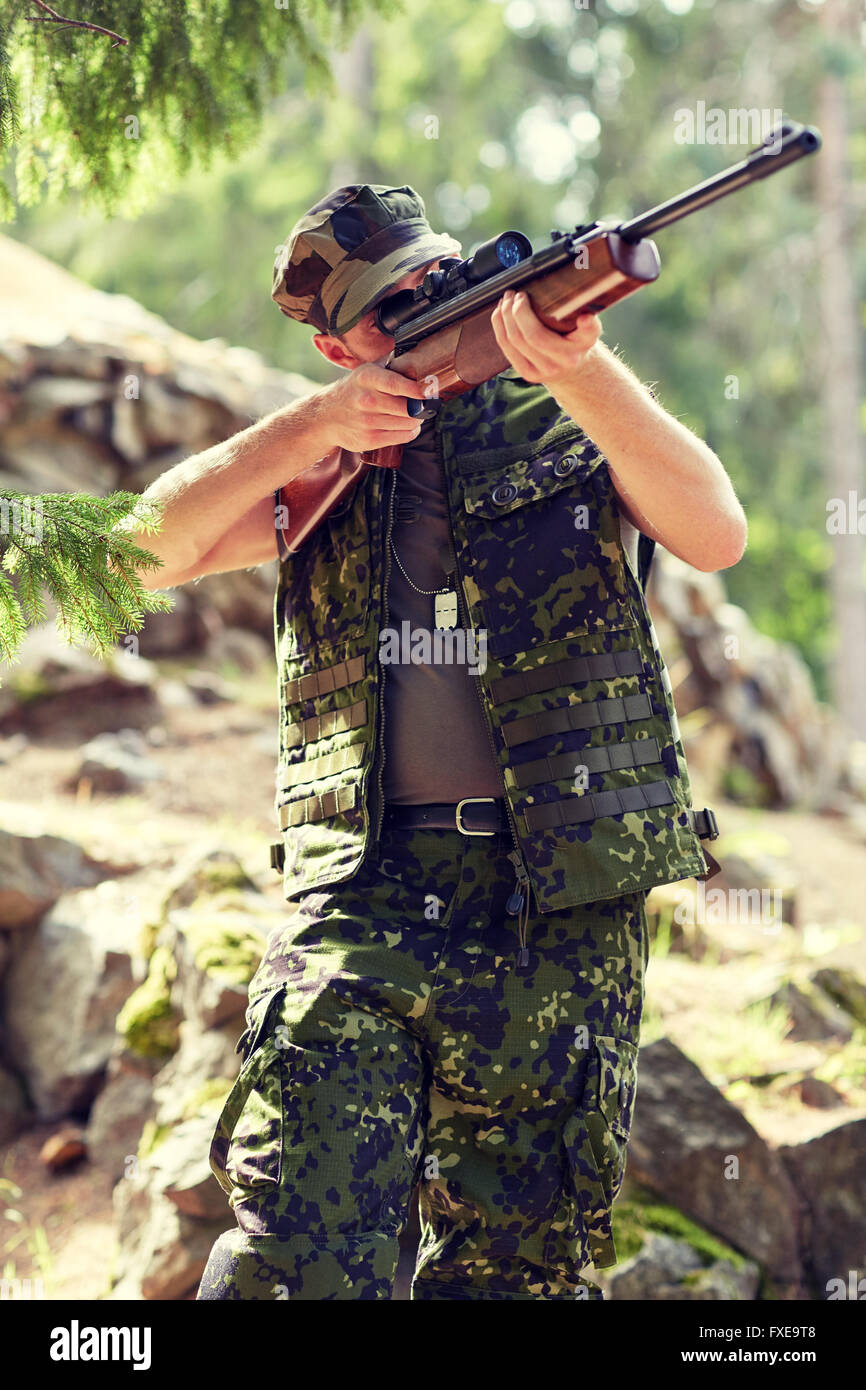 soldier or hunter shooting with gun in forest Stock Photo - Alamy