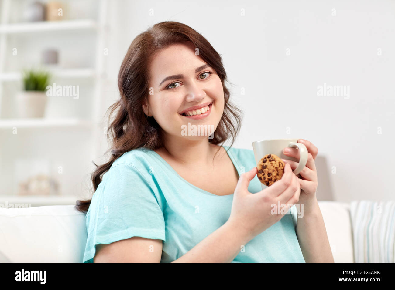 happy plus size woman with cup and cookie at home Stock Photo - Alamy