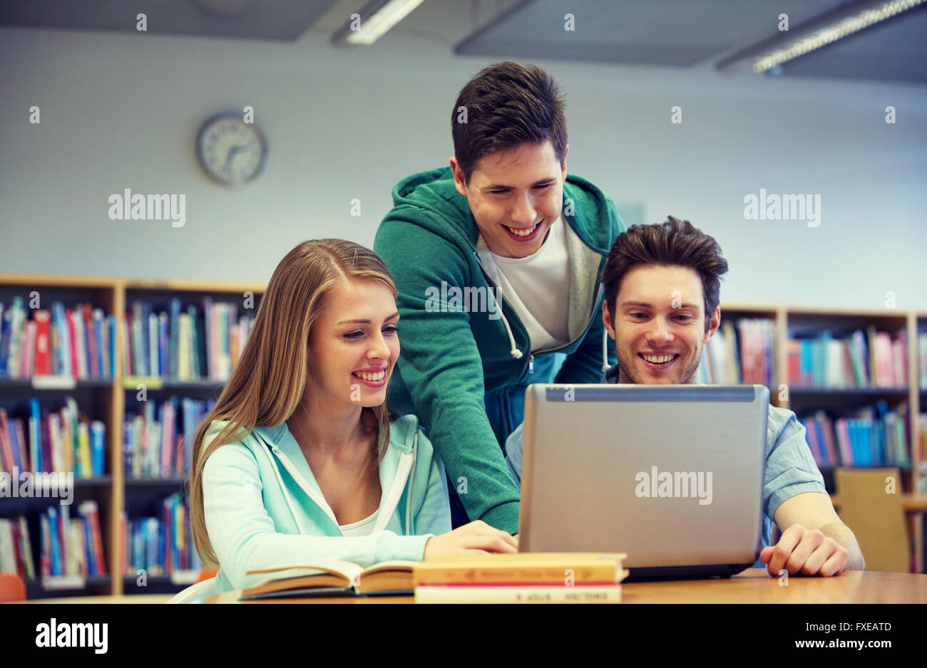 happy students with laptop in library Stock Photo - Alamy