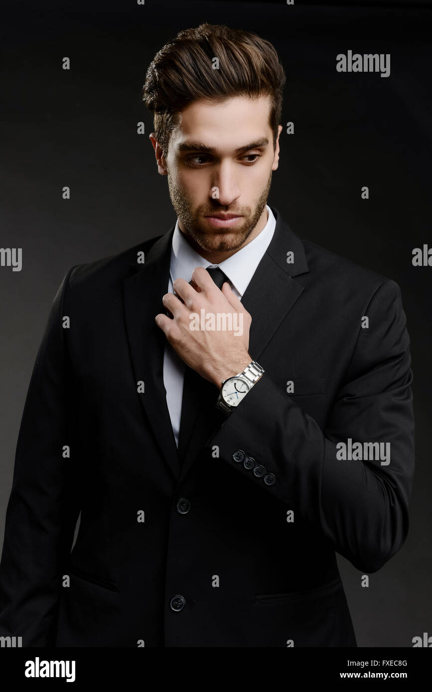 Male model in black suit against black background Stock Photo - Alamy