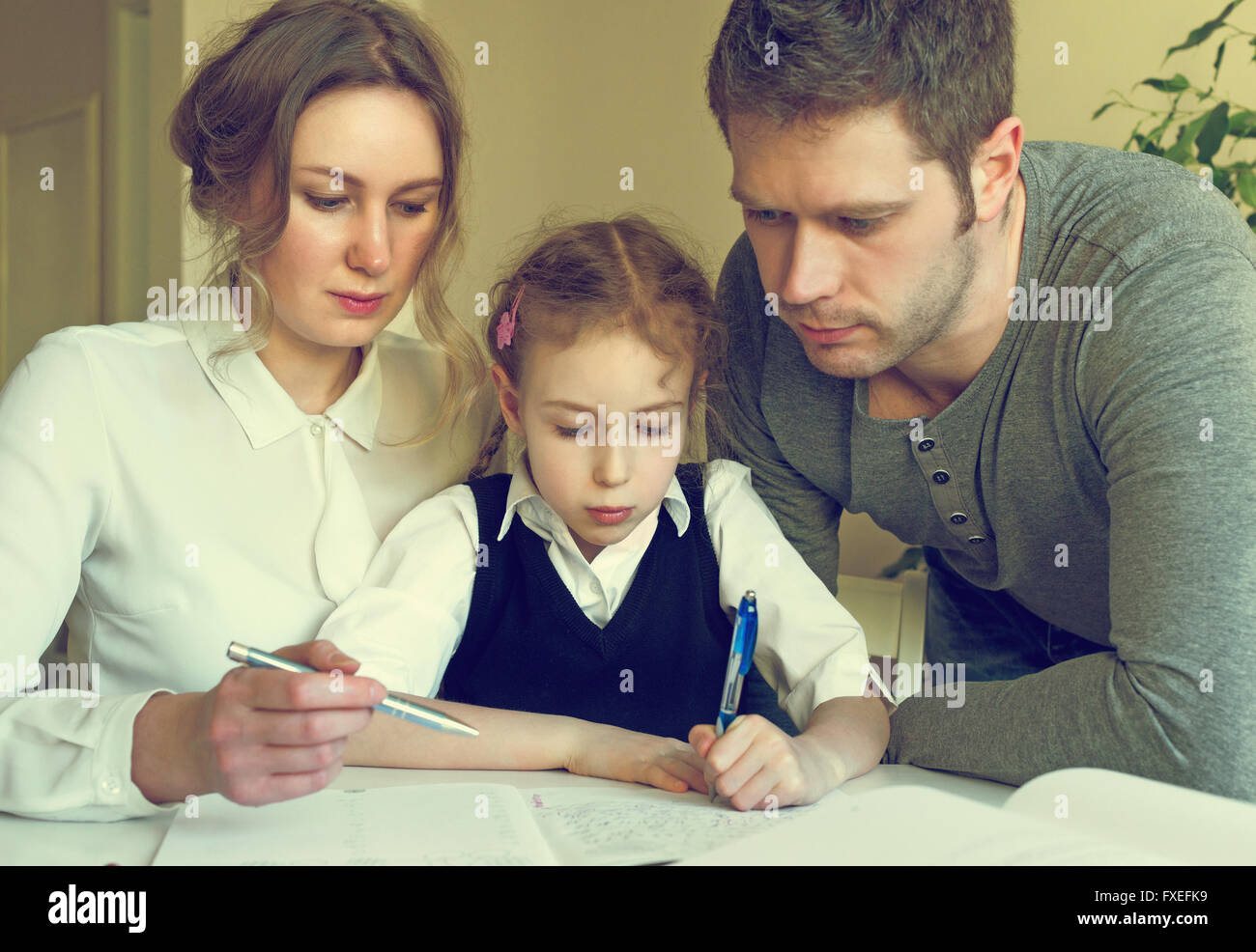 Mother and father helping daughter with homework at home Stock Photo ...