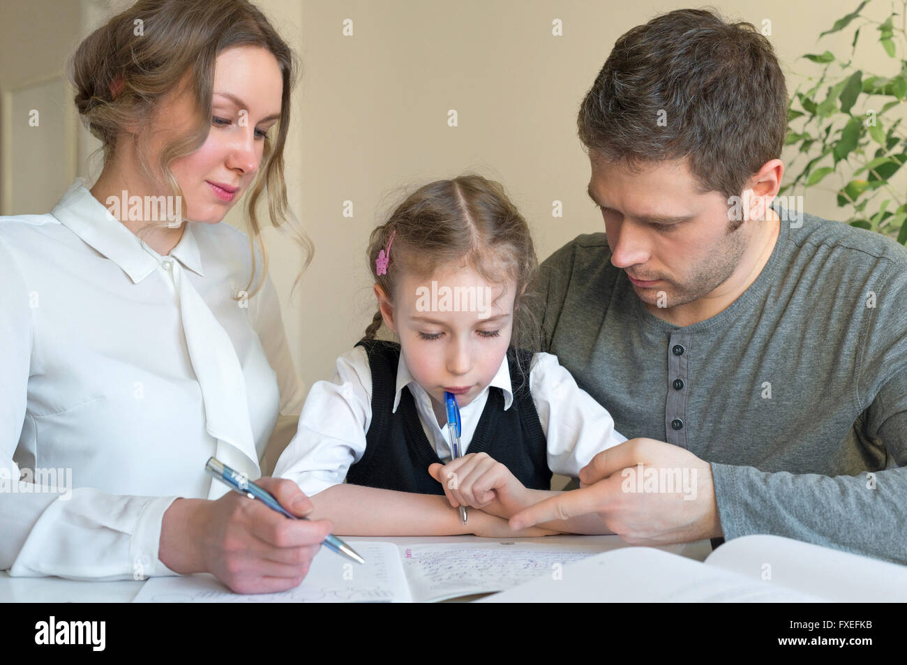 Mother and father helping daughter with homework at home Stock Photo ...