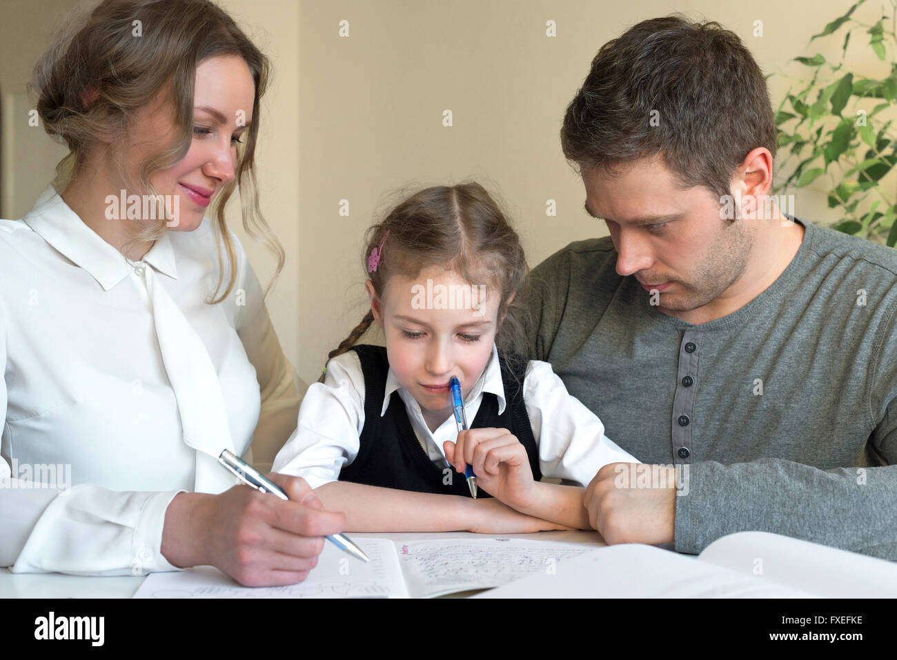 Mother and father helping daughter with homework at home Stock Photo ...