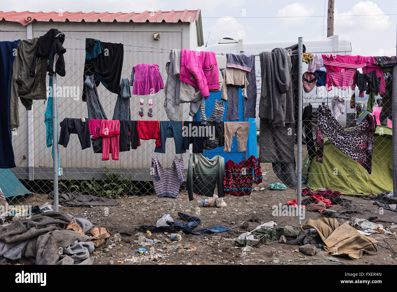 Refugees and immigrants try to dry their clothes after heavy rain on ...