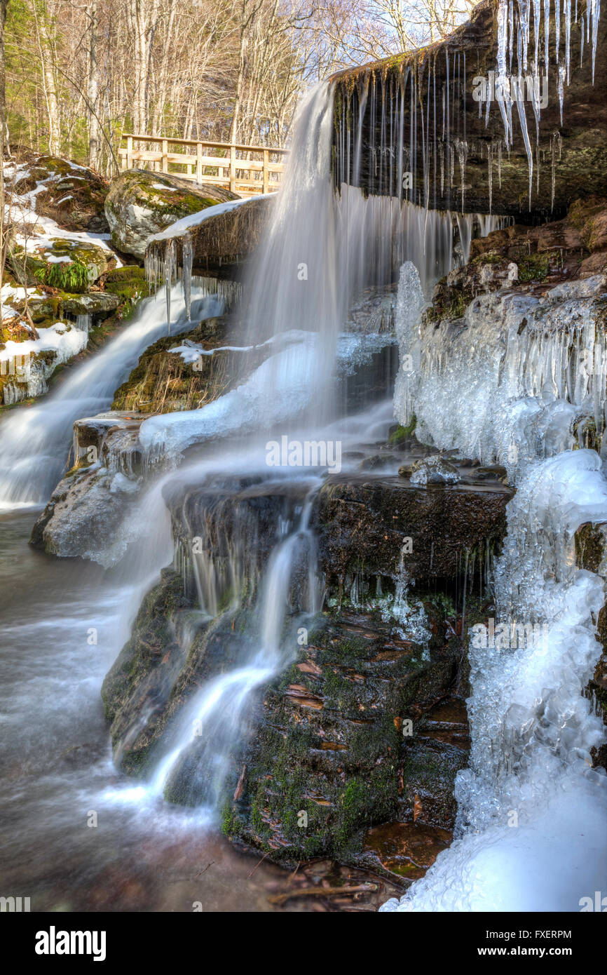 Water falls gently over rocky strata at partially frozen West Kill ...