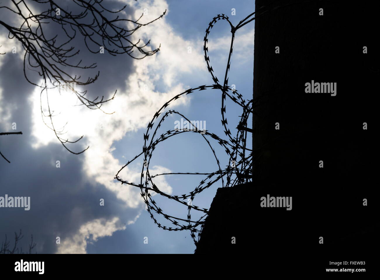 Dramatic clouds behind barbed wire fence on a prison wall Stock Photo ...