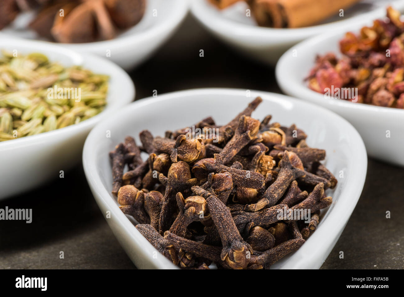 Cloves in white spoon with other Chinese five spice ingredients ...