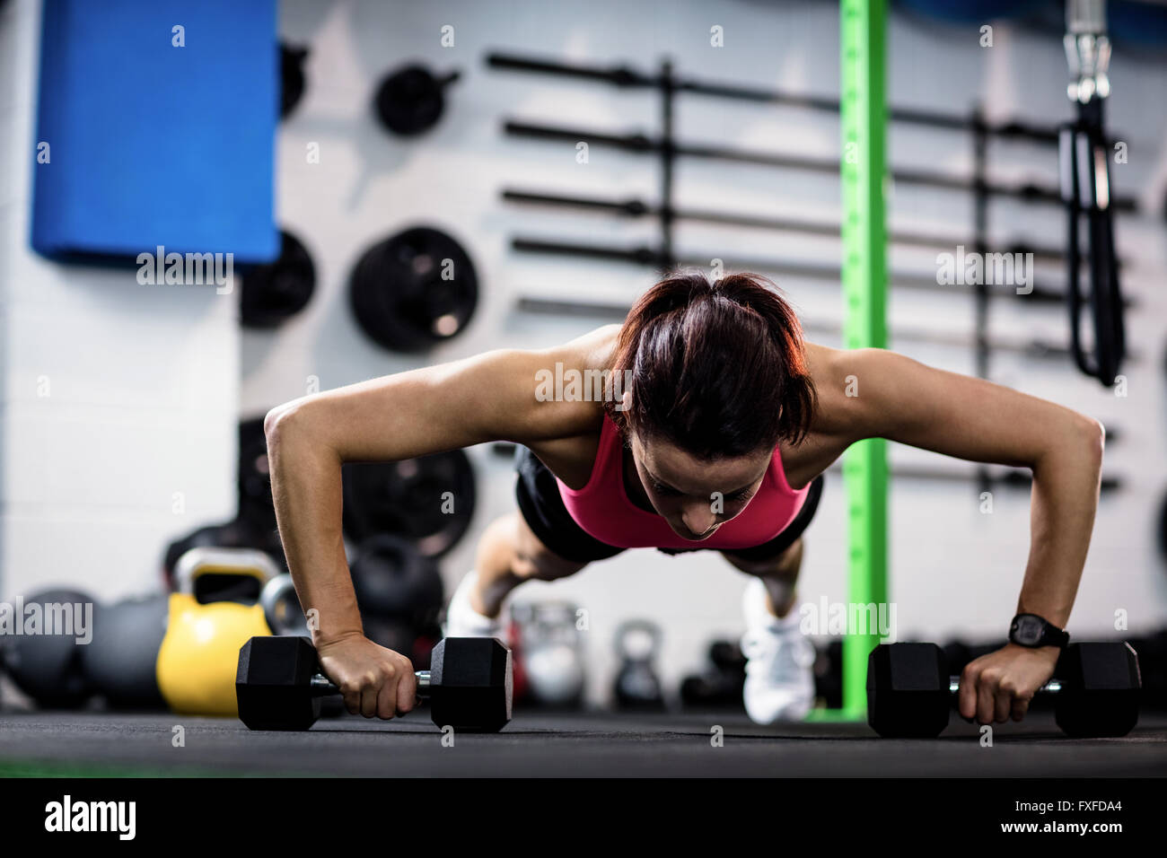 Determined woman doing push ups with dumbbell Stock Photo - Alamy