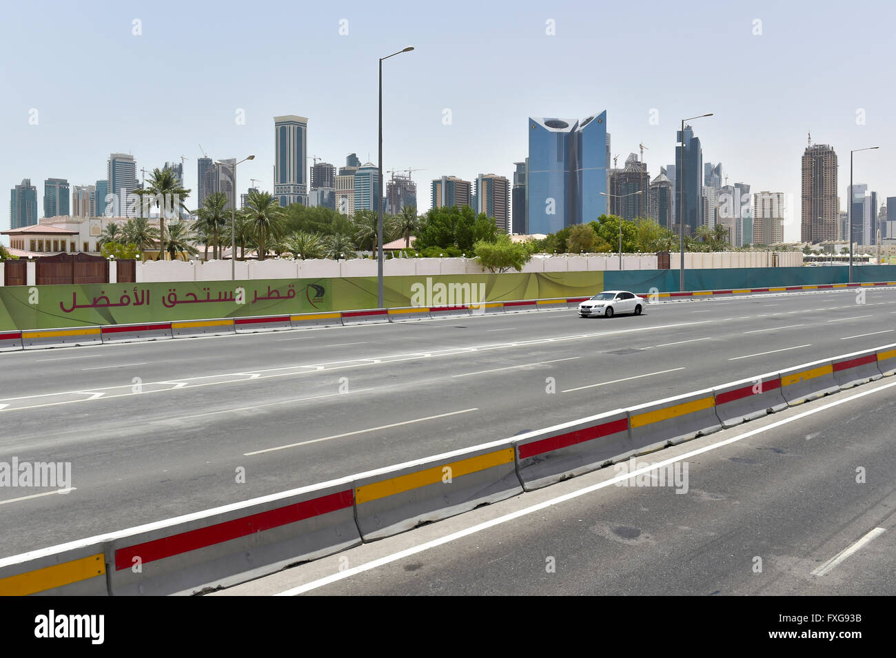 Car on a road with five lanes in front of the skyline of Doha, Qatar ...