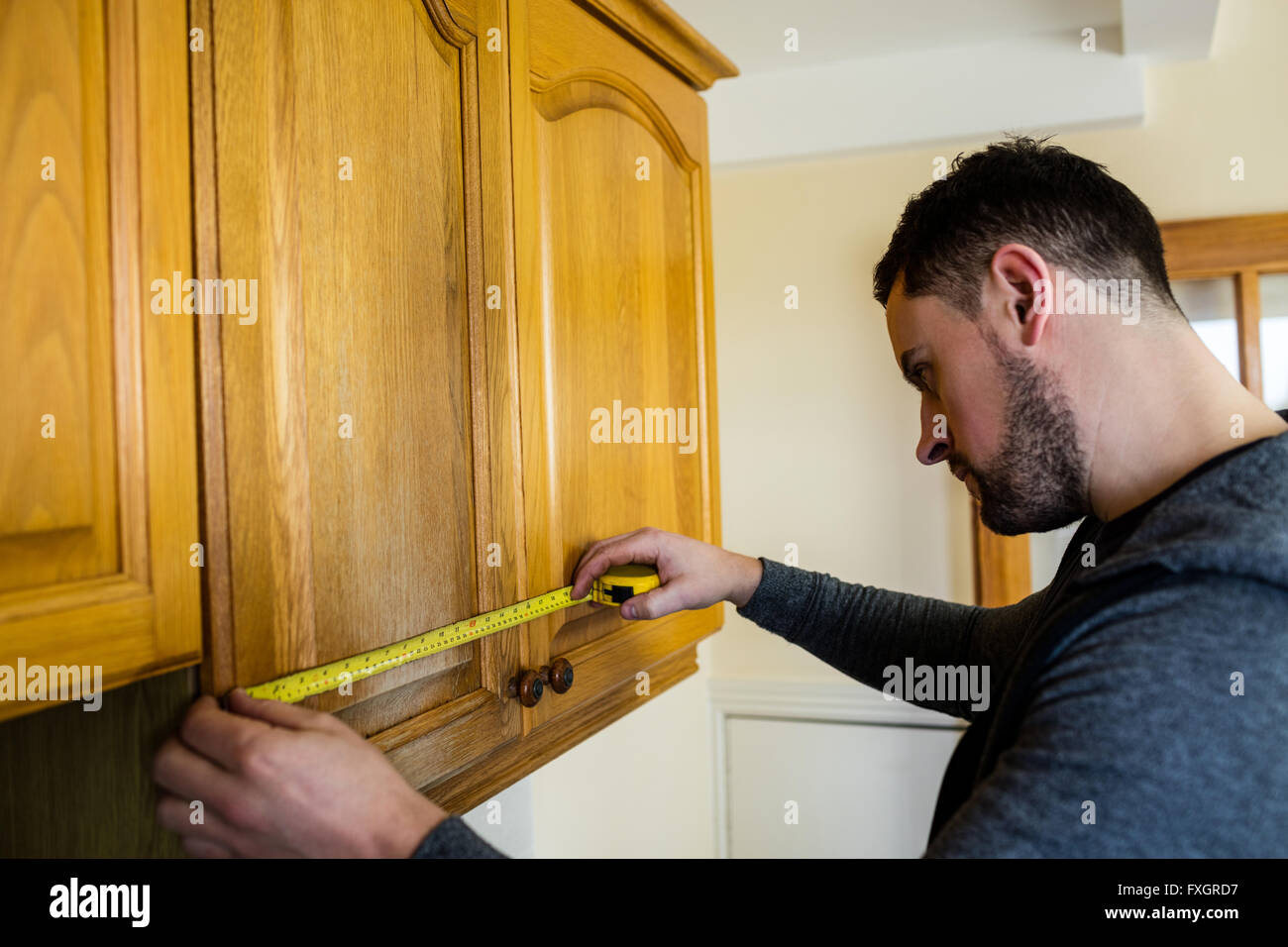Handyman measuring a furniture with measuring tape Stock Photo - Alamy
