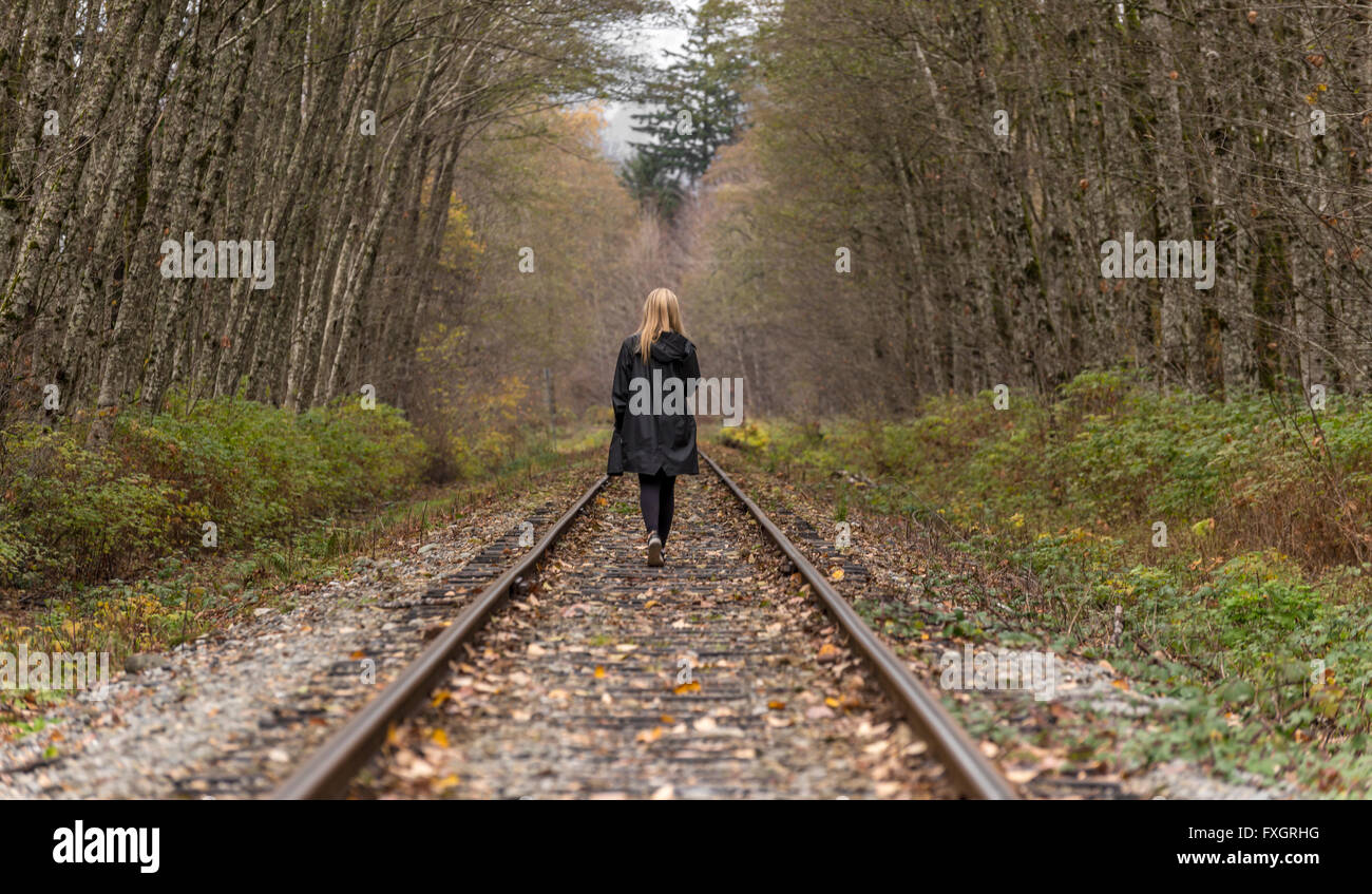 Young female walking down train tracks in the forest Stock Photo - Alamy