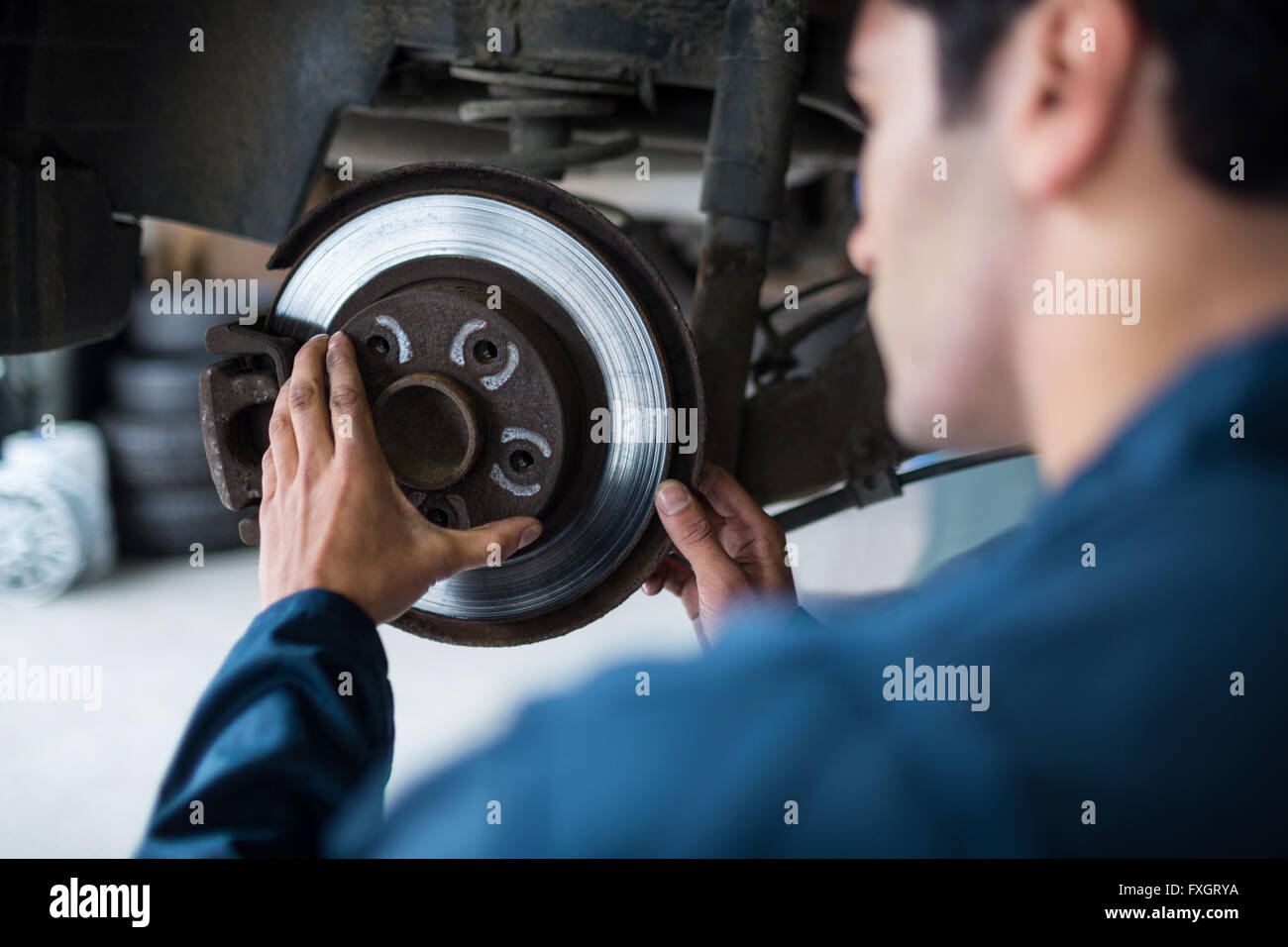 Mechanic examining car brake Stock Photo - Alamy