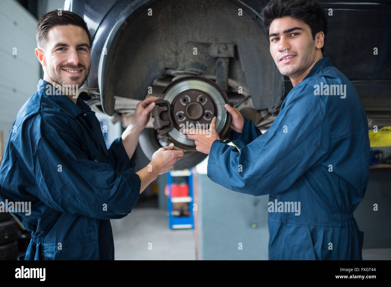 Mechanics examining car brake Stock Photo - Alamy