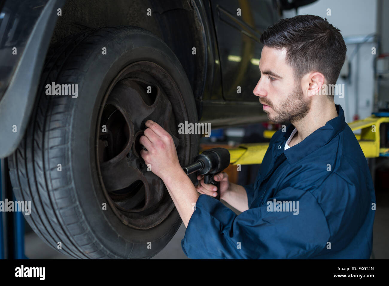 Mechanic changing car wheel with pneumatic wrench Stock Photo - Alamy