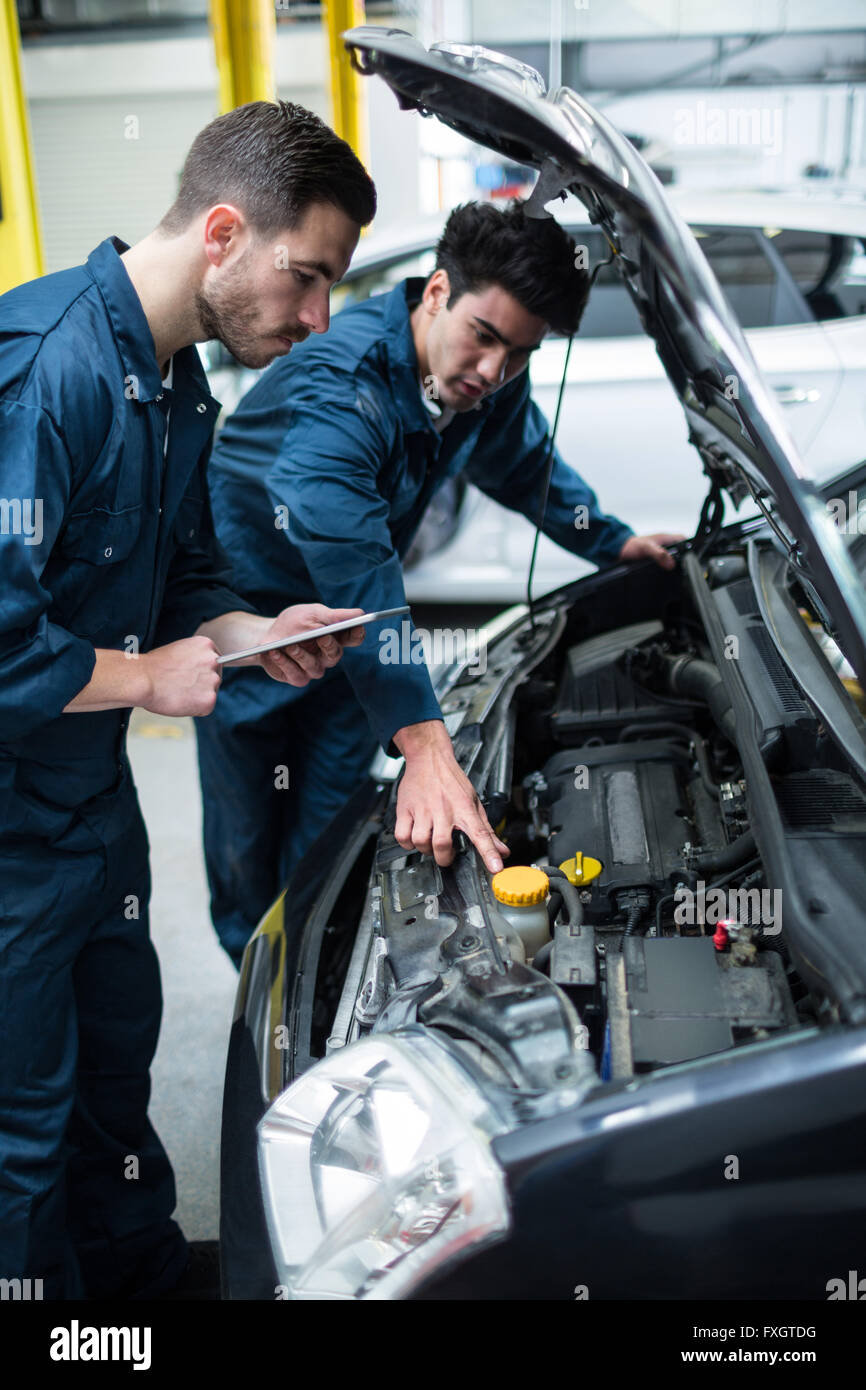 Mechanics examining car engine using digital tablet Stock Photo - Alamy
